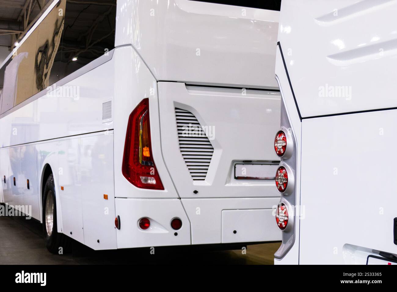 The image shows two white tourist buses parked next to each other. The ...