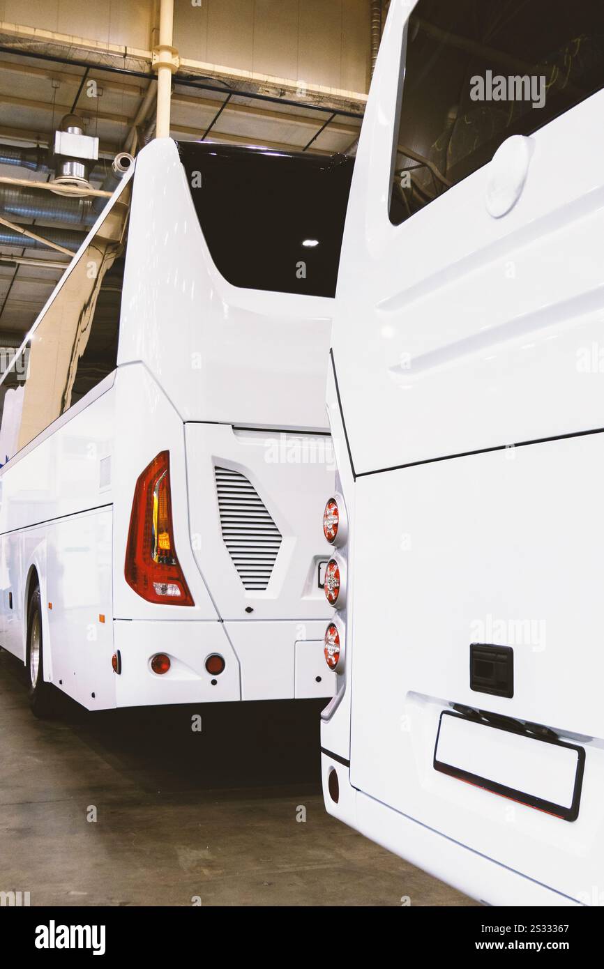 The image shows two white tourist buses parked next to each other. The ...