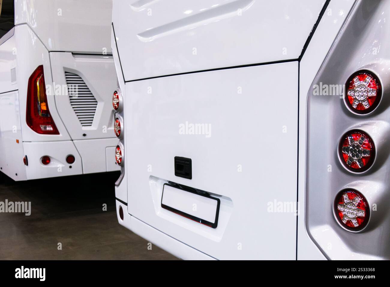 The image shows two white tourist buses parked next to each other. The ...