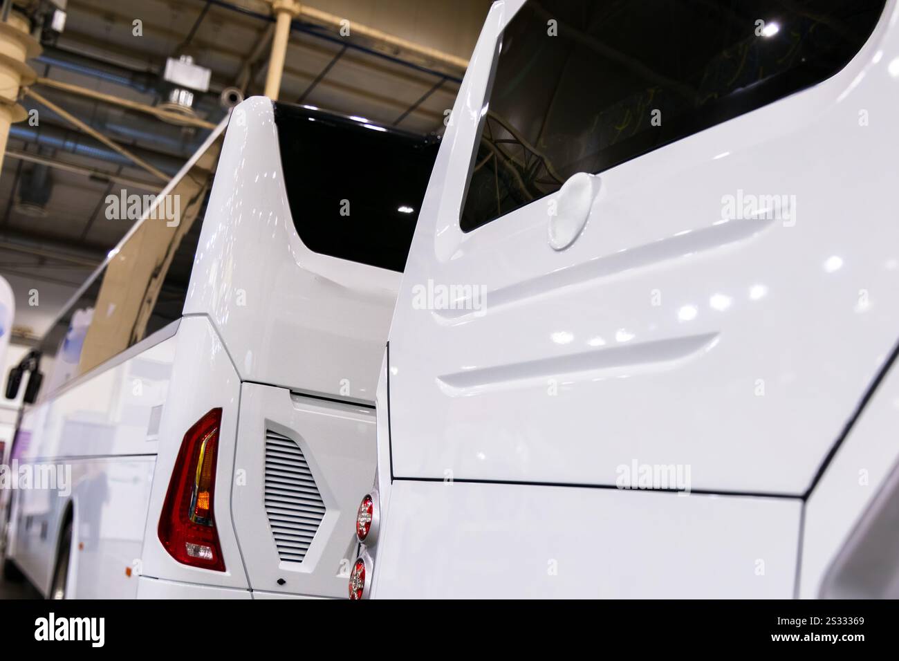 The image shows two white tourist buses parked next to each other. The ...