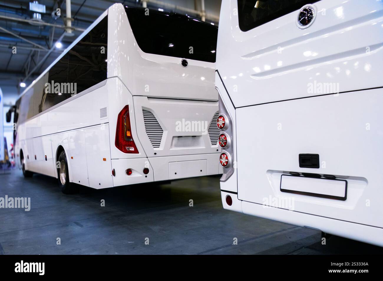 The image shows two white tourist buses parked next to each other. The ...