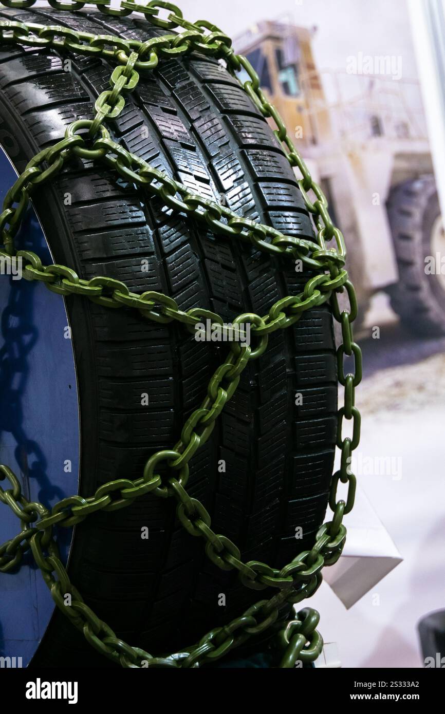 A car tire with green snow chains. The tire is black with a clear tread ...