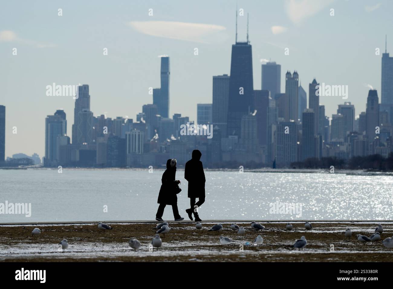 Pedestrians bundle up as they walk along the shore of Lake Michigan at ...