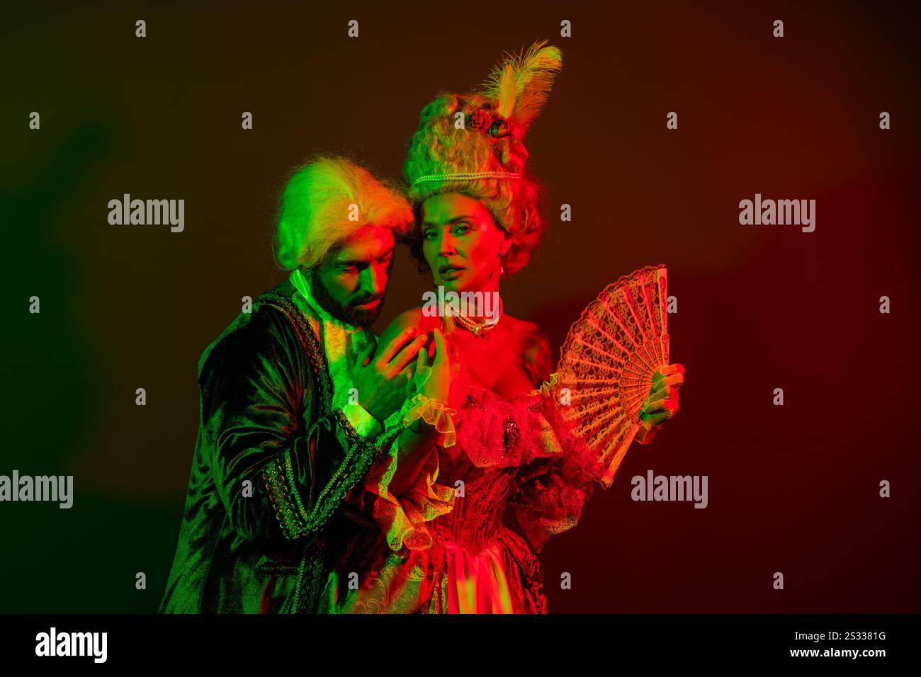 Elegant couple in historical costume illuminated by dramatic red and ...