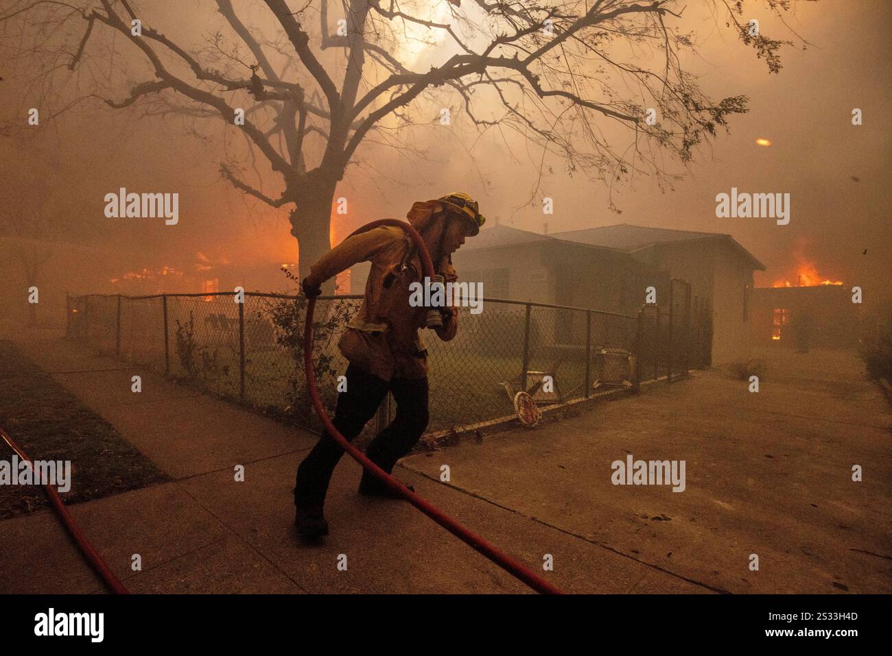 A firefighter protects a structure as the Eaton Fire advances Wednesday ...