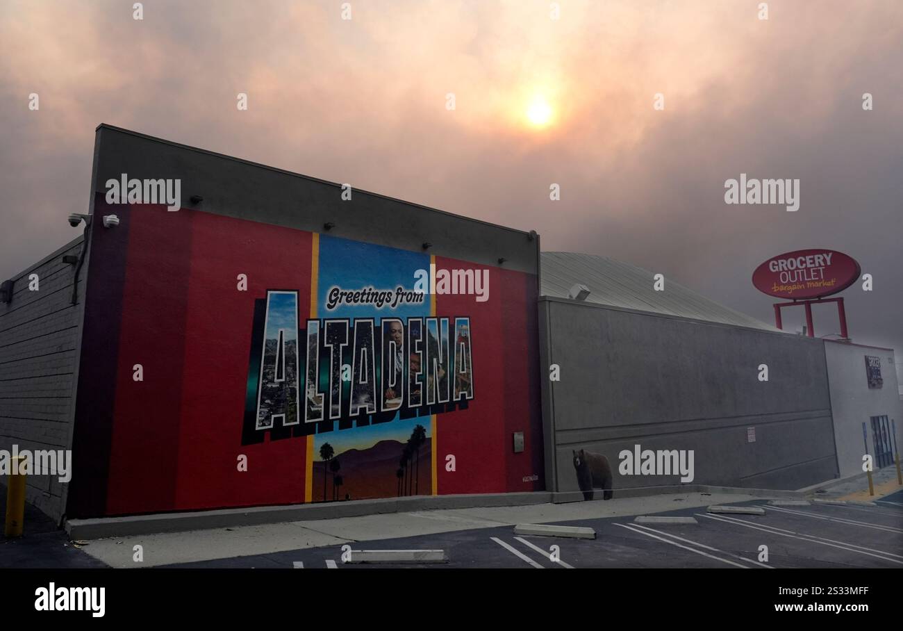 Smoke billows behind a sign welcoming visitors to the Altadena section ...