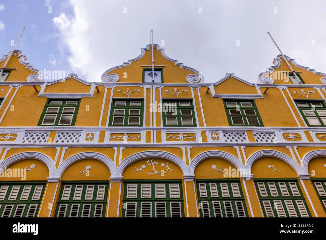 Historic yellow Dutch colonial building facade with green shutters in ...
