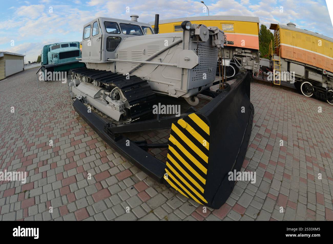 Photo of a gray bulldozer among the railway trains. Strong distortion ...