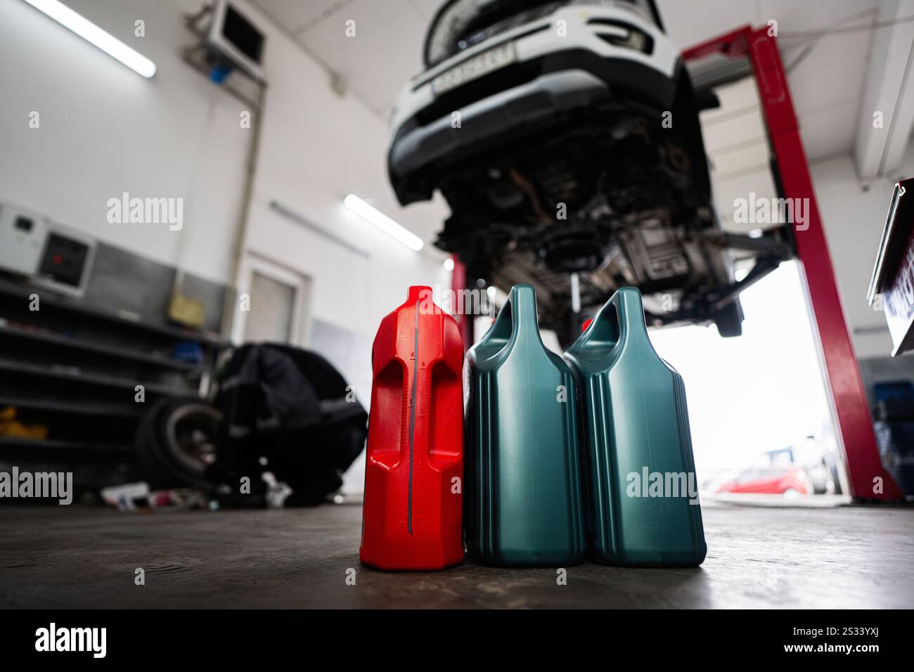 Car oil containers in a mechanic's shop with a vehicle lifted on a ...