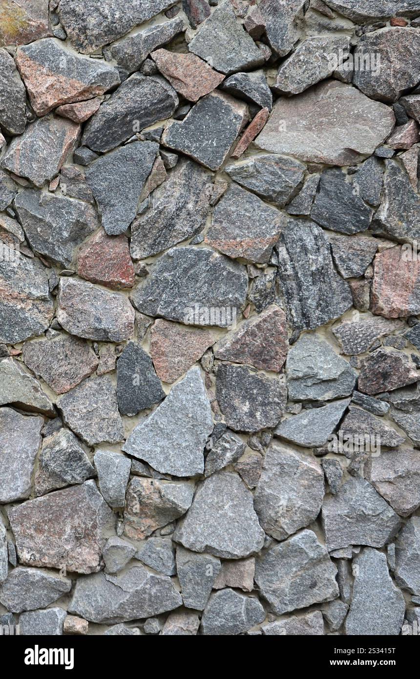 The texture of a strong stone wall of many concreted stones of various ...