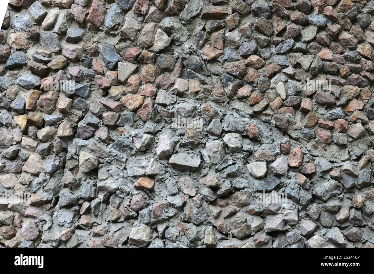 The texture of a strong stone wall of many concreted stones of various ...