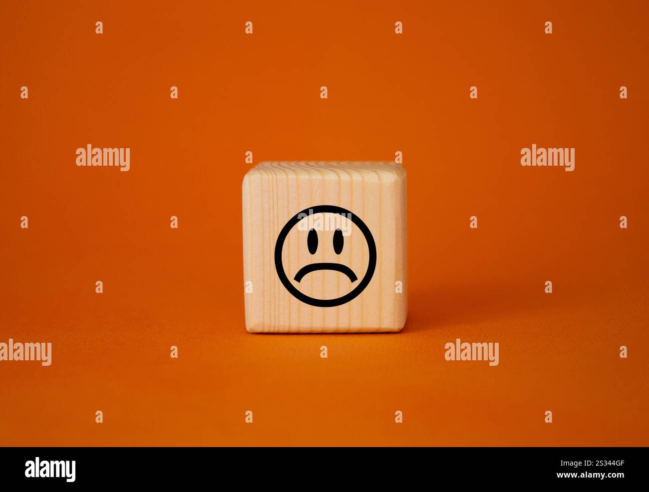 Sad smile symbol. Sad smile on wooden cube. Beautiful orange background ...