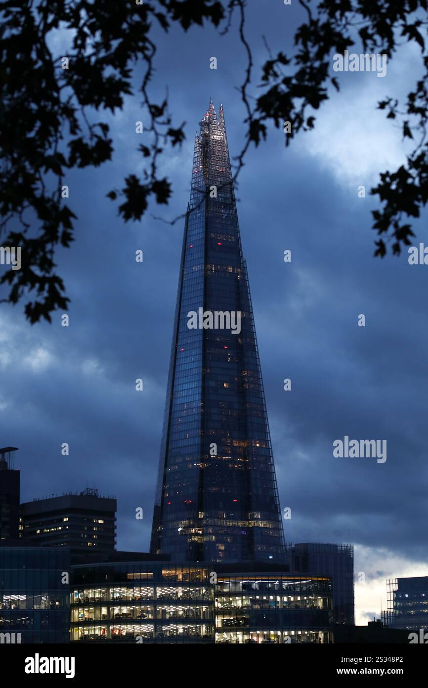 The Shard London with illuminated spire at night framed by trees Stock ...