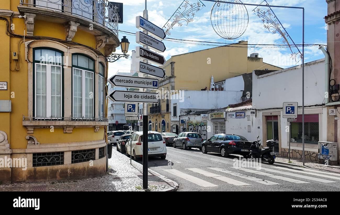 a direction sign mounted on a pole, located outdoors in faro, portugal ...