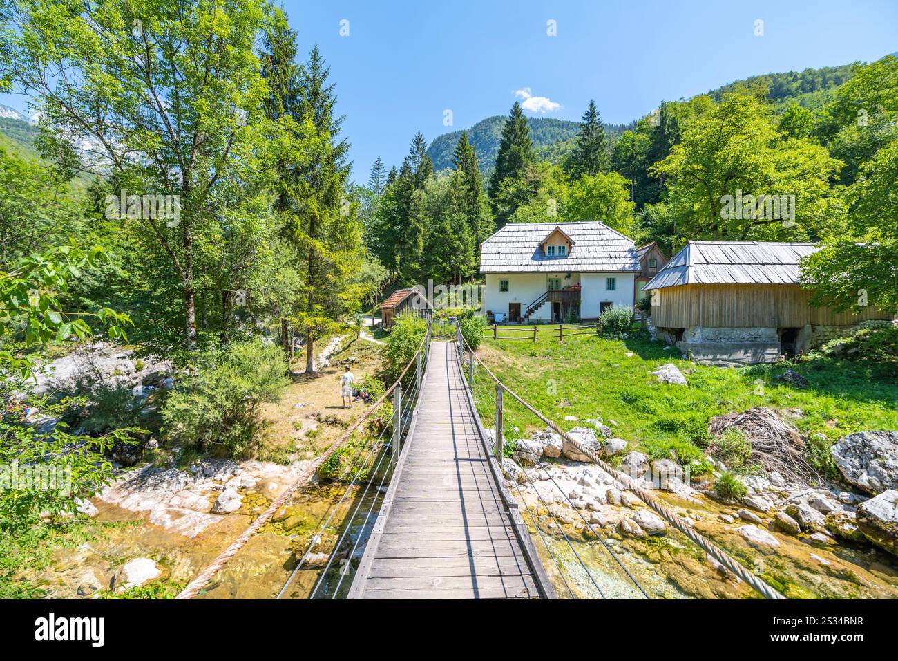 Hikers traverse a wooden bridge spanning Vrsnica creek in the Soca ...