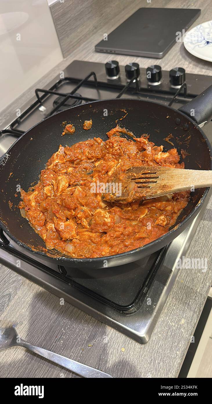 A delicious homemade chicken Thai satay curry being cooked in a black ...