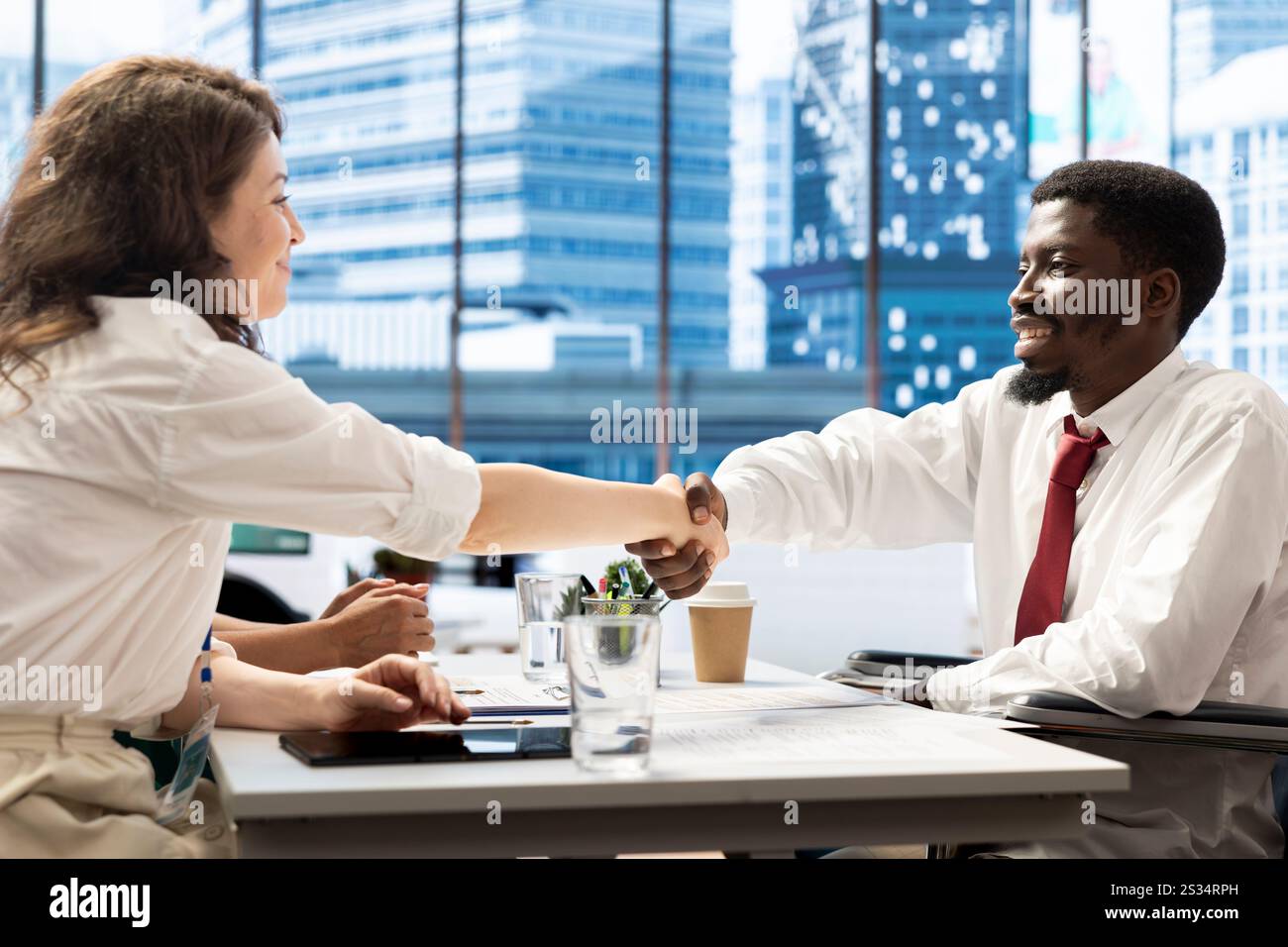 HR expert doing handshake with person with disability, vetting applicants to ensure skills match ...