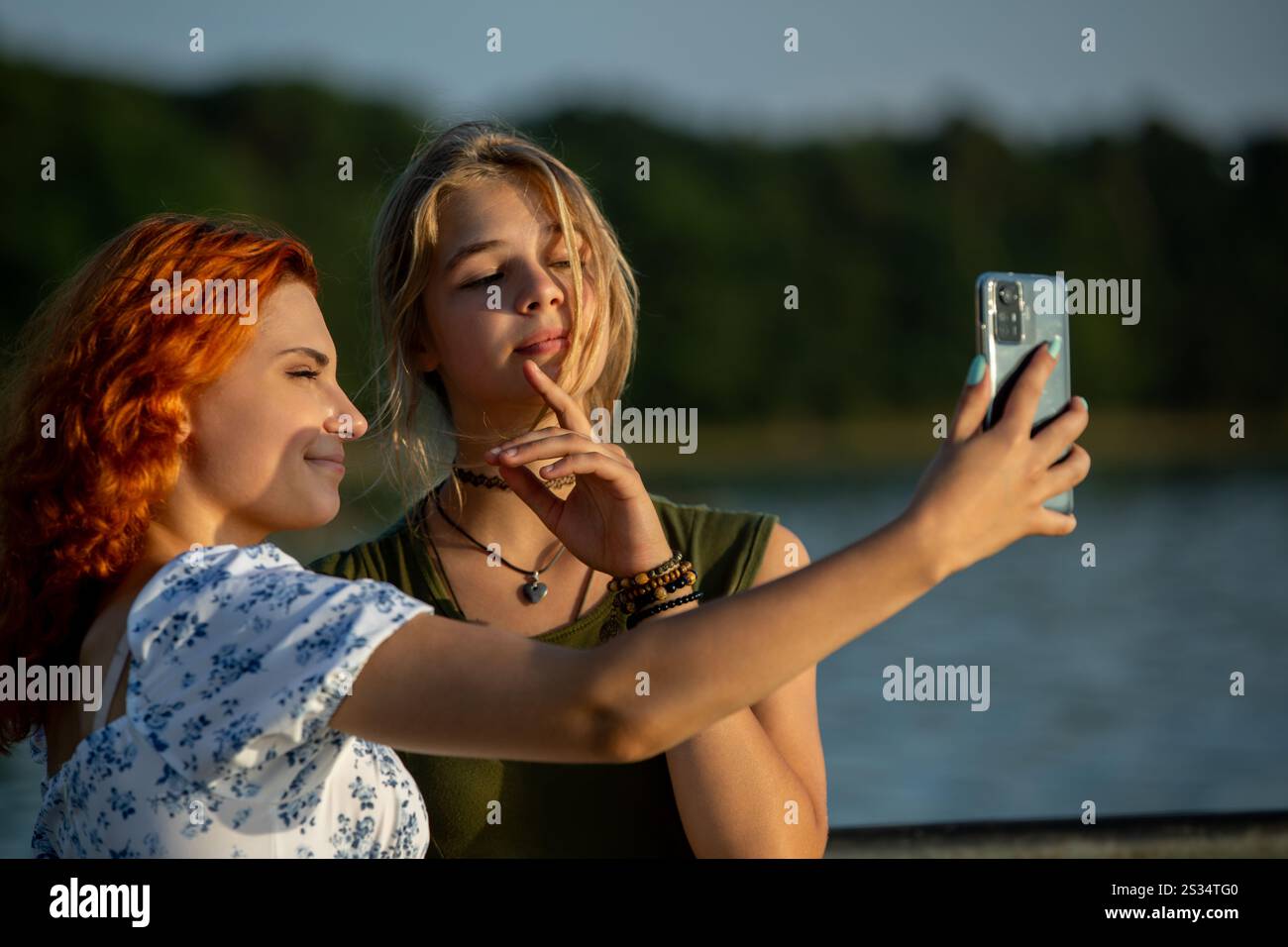 Two close friends joyfully taking a vibrant selfie together by the ...