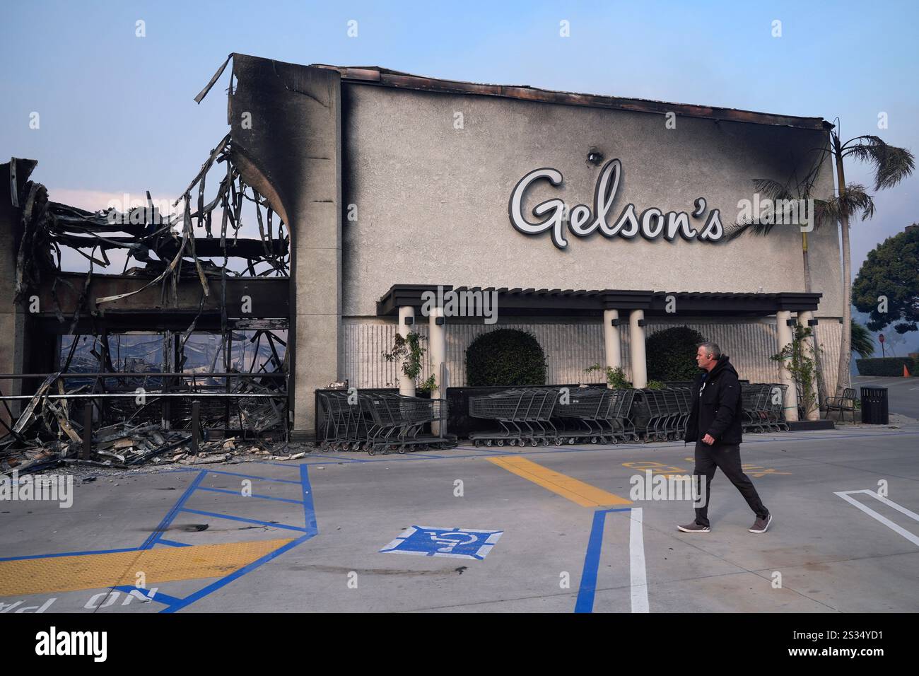 A man walks by Gelson's as the Palisades Fire ravages a neighborhood ...