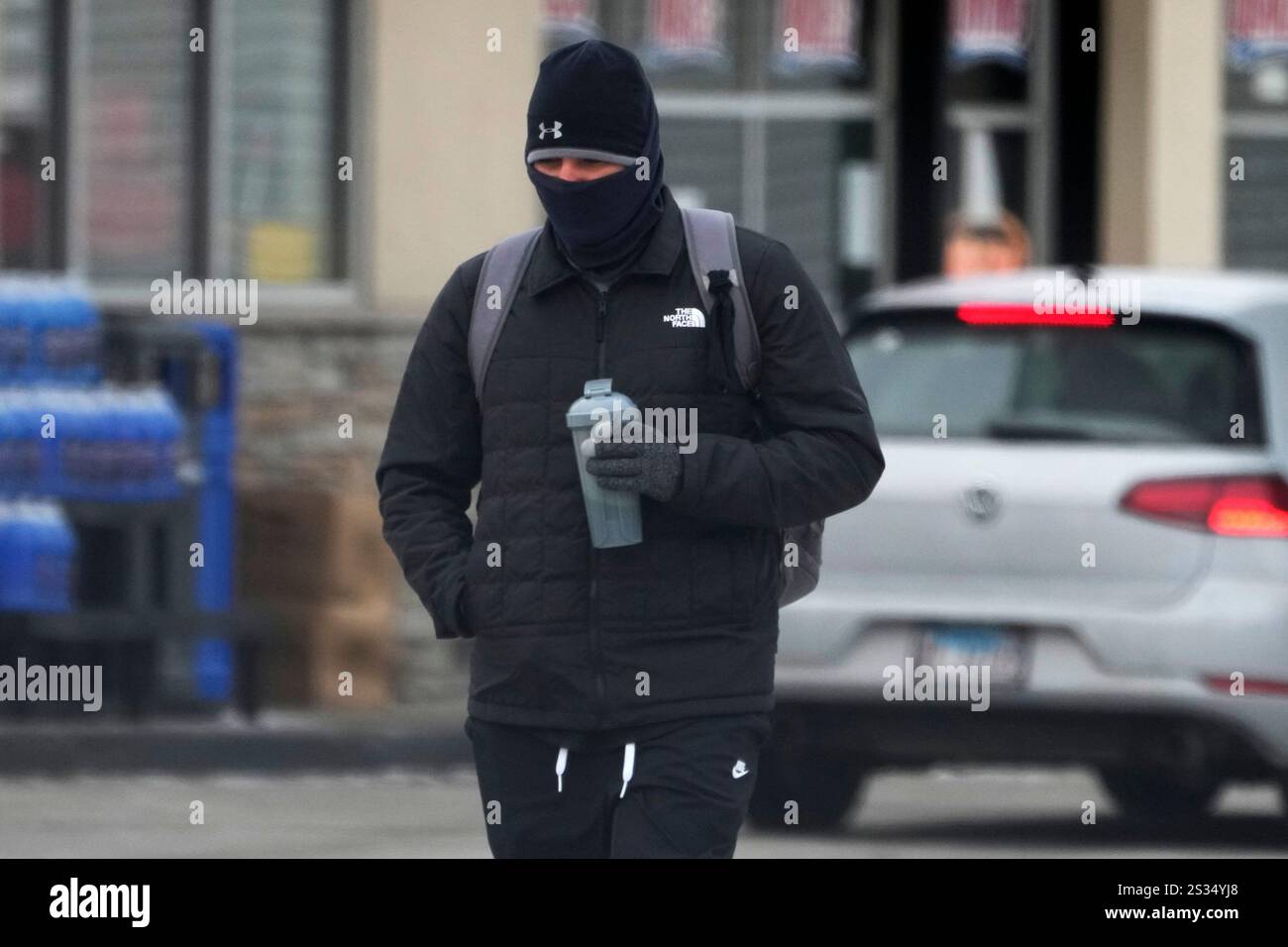 A pedestrian bundles up as he walks on the street during cold weather ...