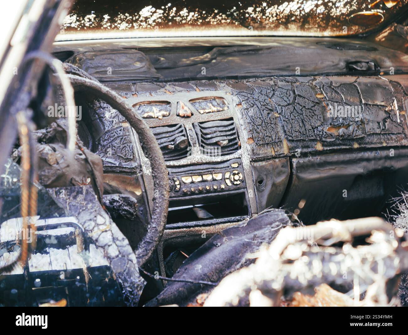 A close-up of a car's interior extensively damaged by fire, featuring a ...
