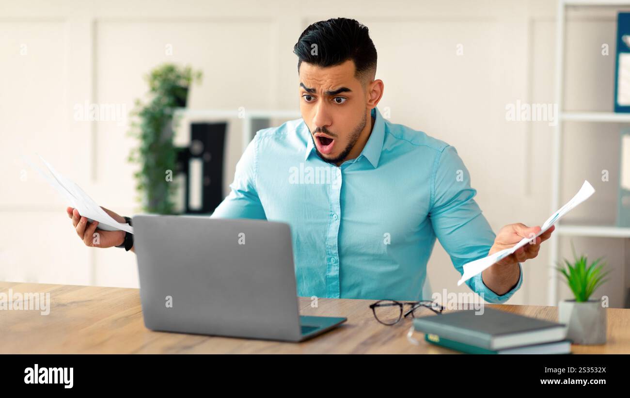 Shocked Arab businessman with documents looking at laptop screen ...