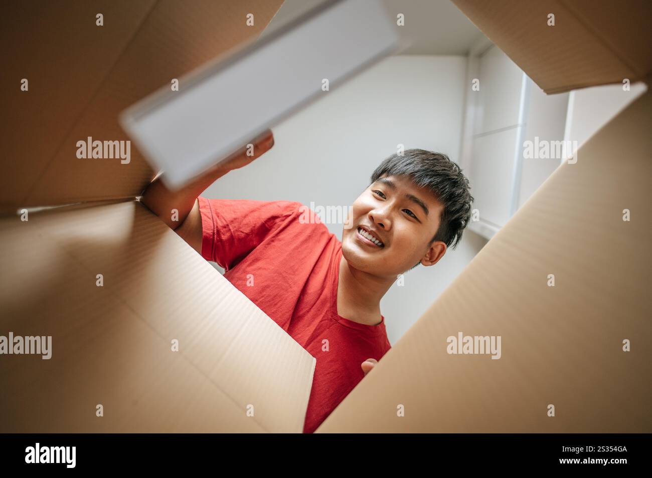 Inside of package view, Smiley young man opens package and grabbing ...
