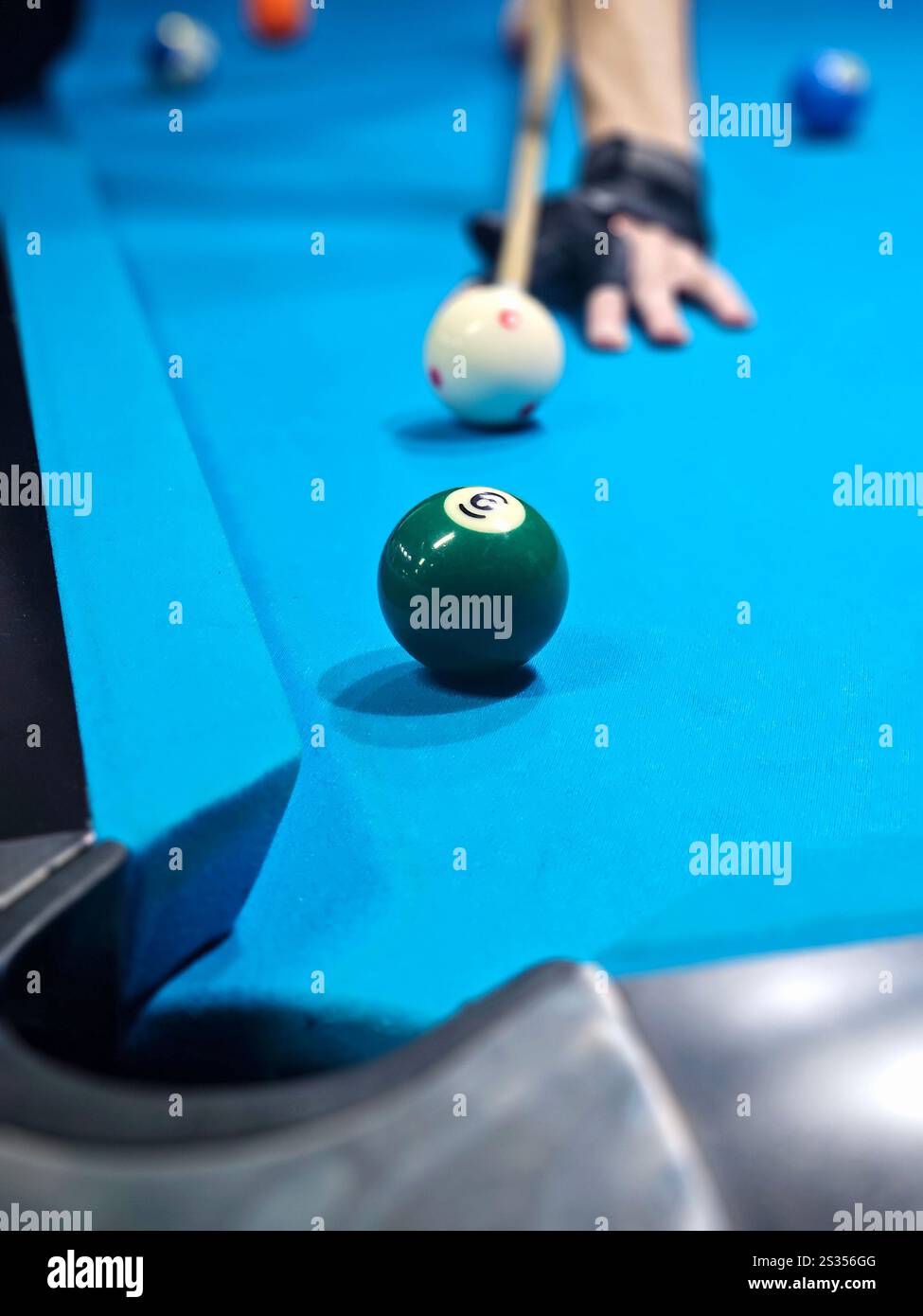 Billiard cue in hands of male player standing by pool table and ...