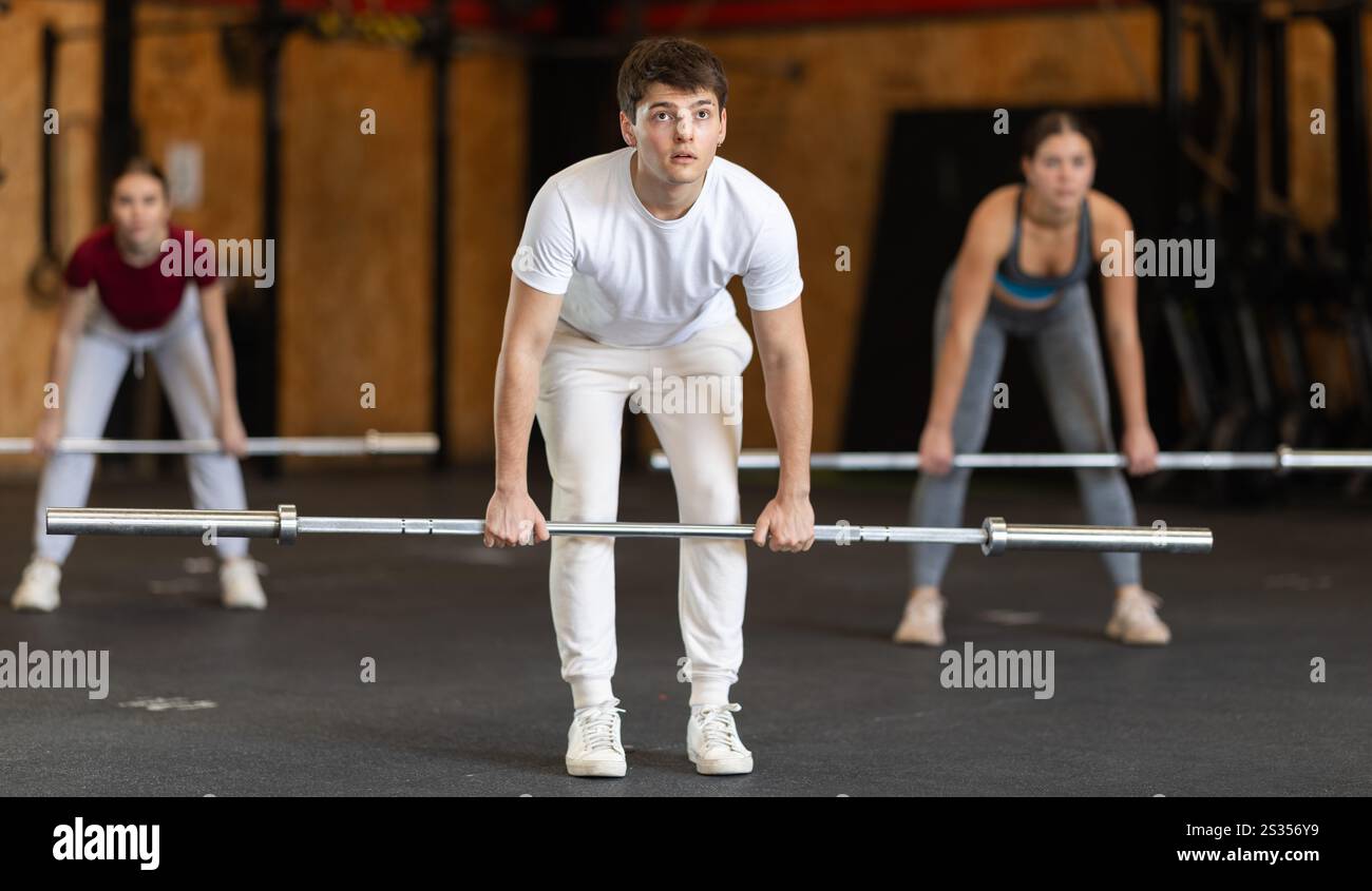 Slender guy trains muscles of arms and back using barbell and ...