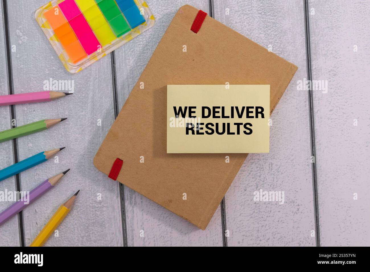 We Deliver Results. text on white paper, on a notepad, on white ...