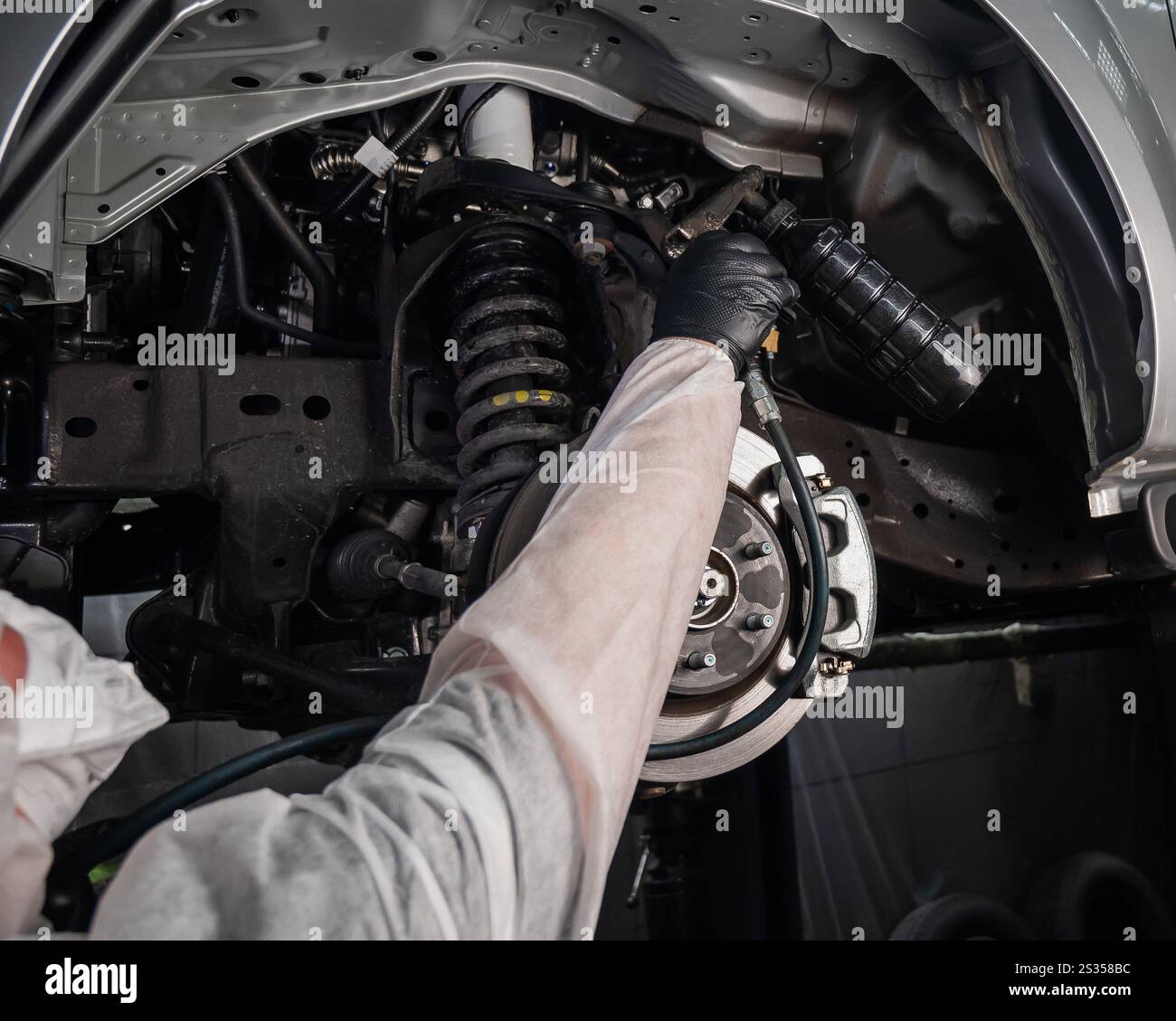 An auto mechanic applies anti-corrosion mastic to the underbody of a ...