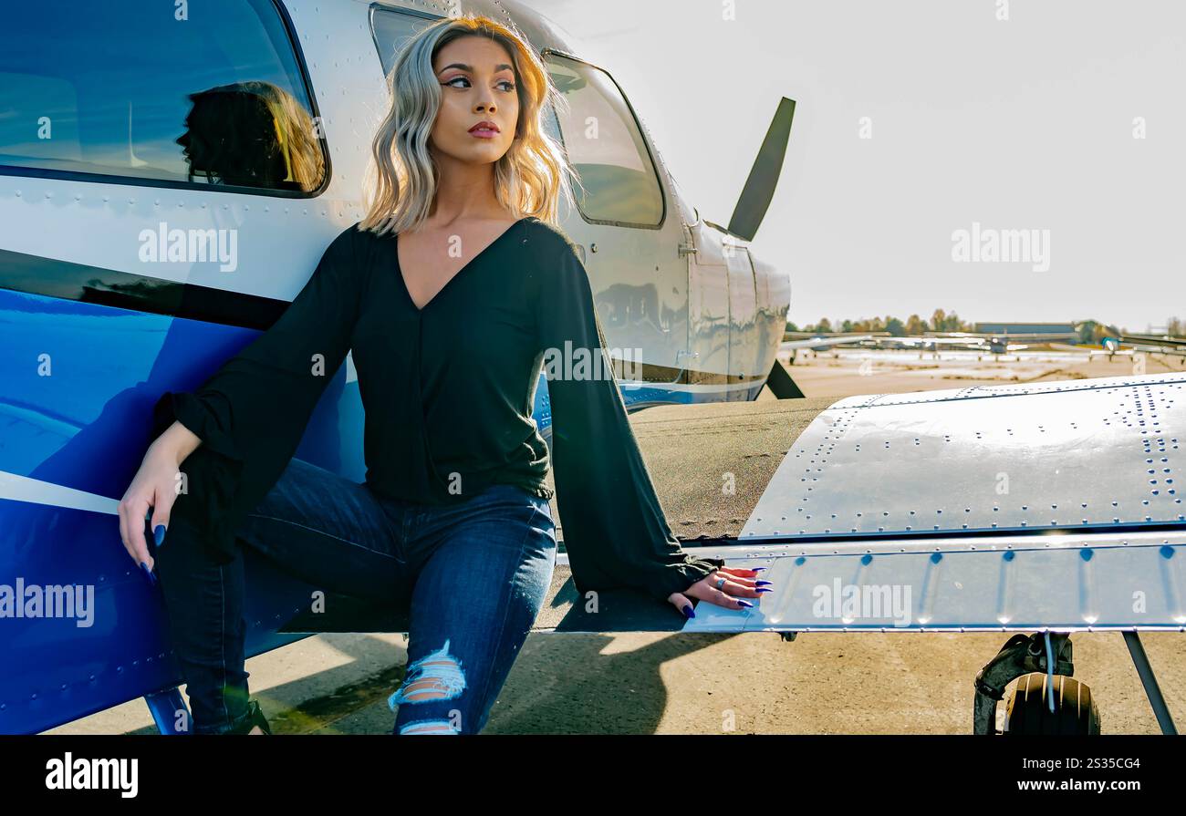 A stunning young woman poses confidently on the tarmac beside a sleek ...