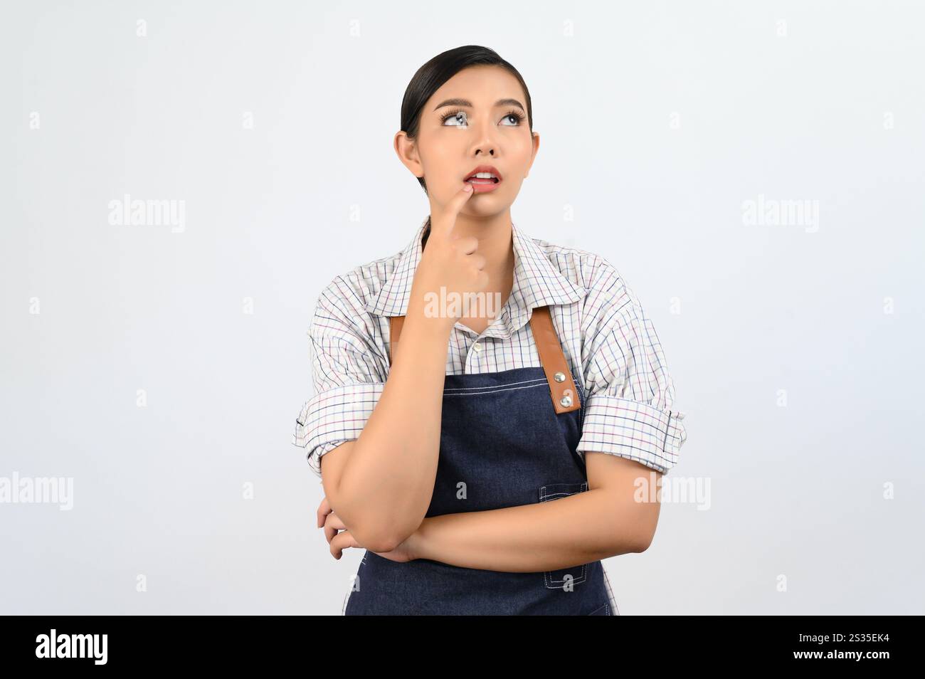Portrait of young asian woman in waitress costume standing and thinking ...