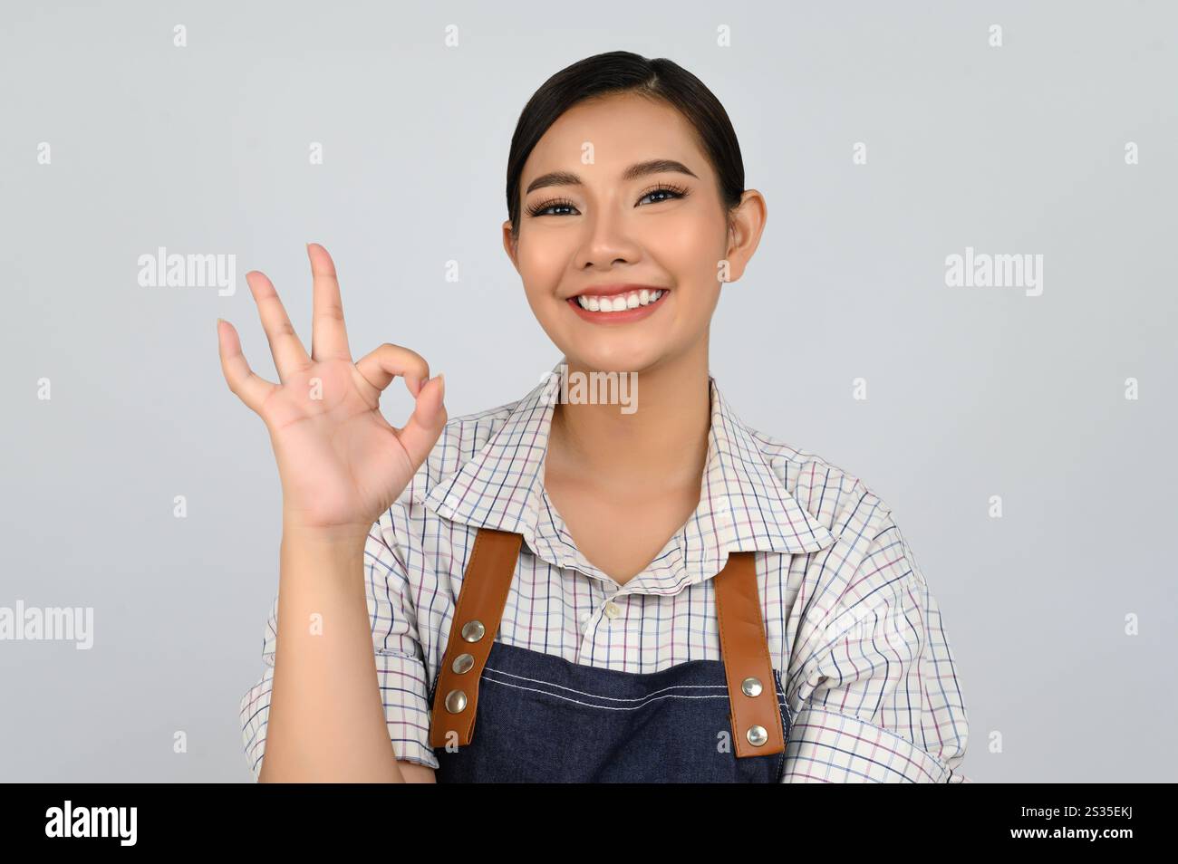 Portrait Asian young woman in waitress uniform and apron showing finger ...