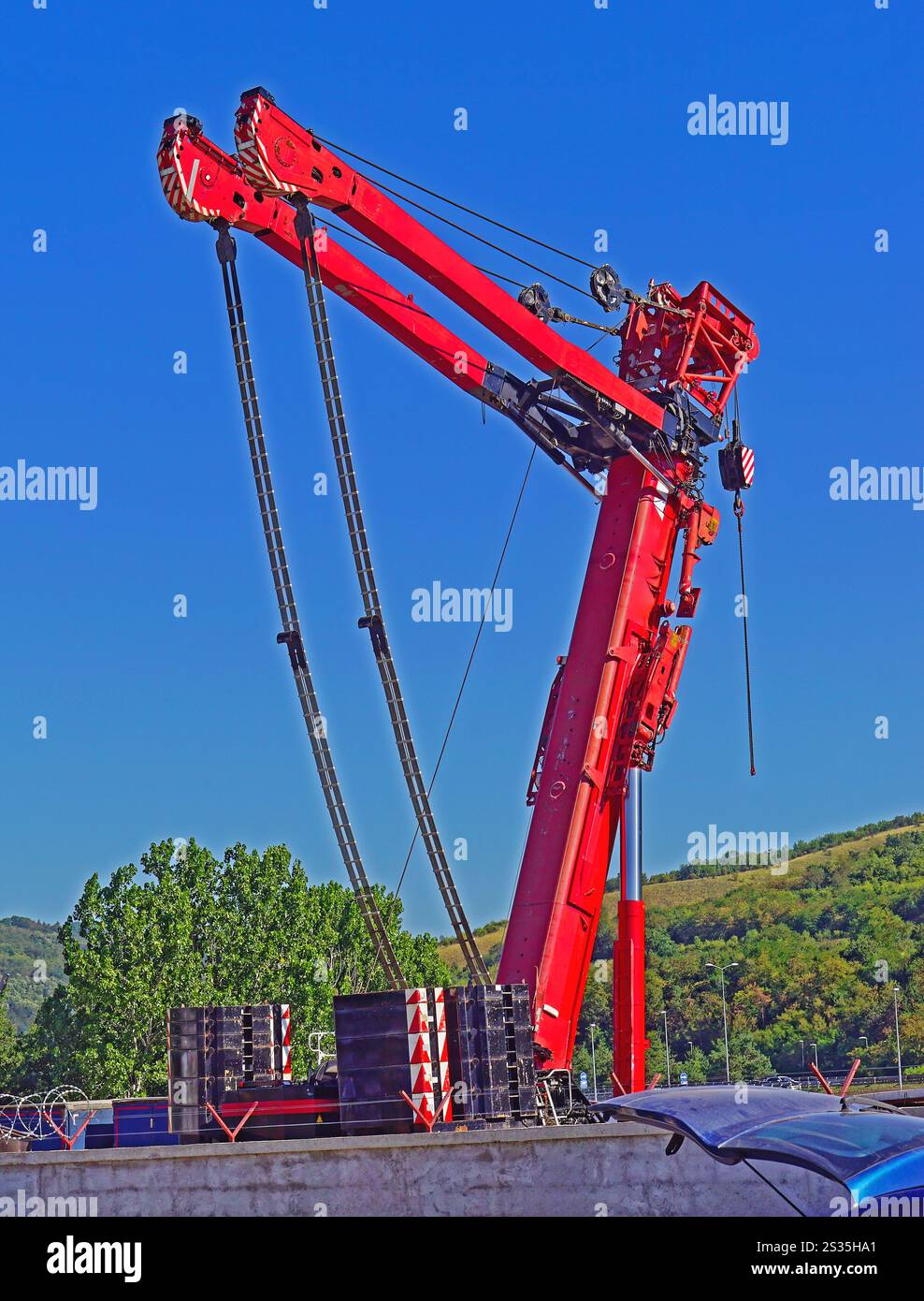 Assembling large red mobile crane boom at construction site sunny day ...