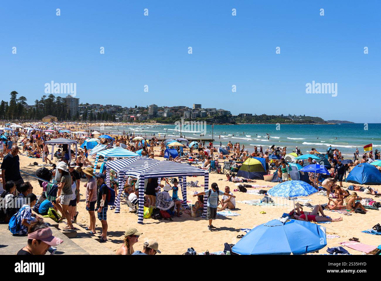 A crowded Manly Beach with cabanas on a hot summer day in Sydney ...