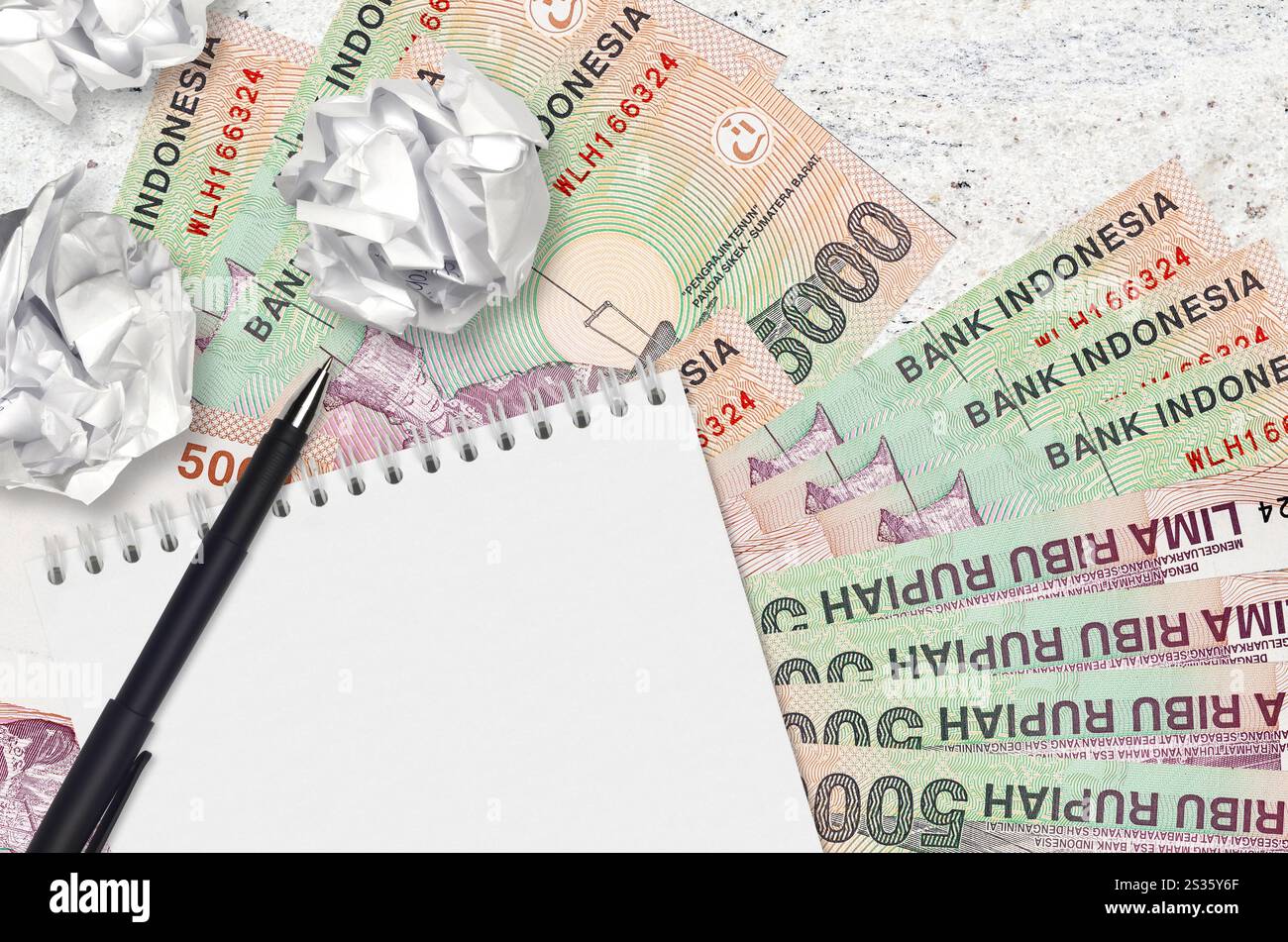 5000 Indonesian rupiah bills and balls of crumpled paper with notepad ...