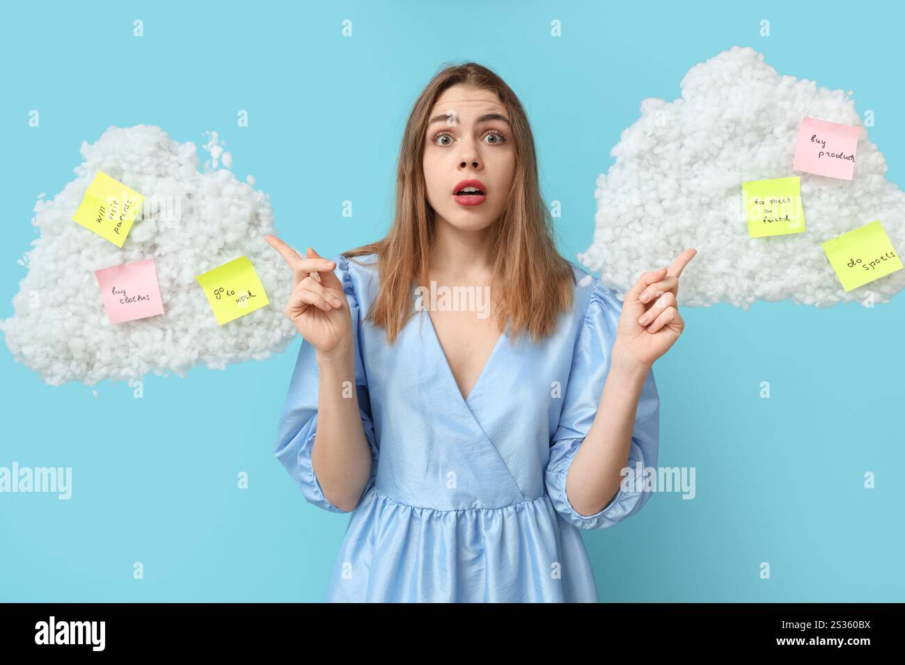 Excited young woman pointing at sticky notes on clouds against blue ...
