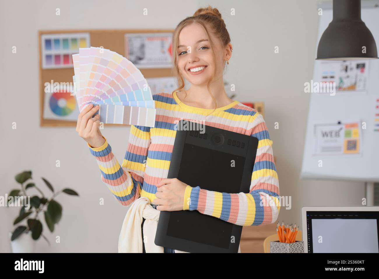 Female web designer with graphic tablet and color palettes in office ...