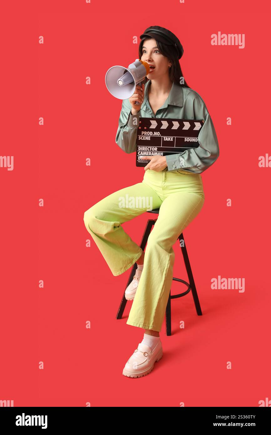 Young shocked female film director with movie clapper and megaphone ...