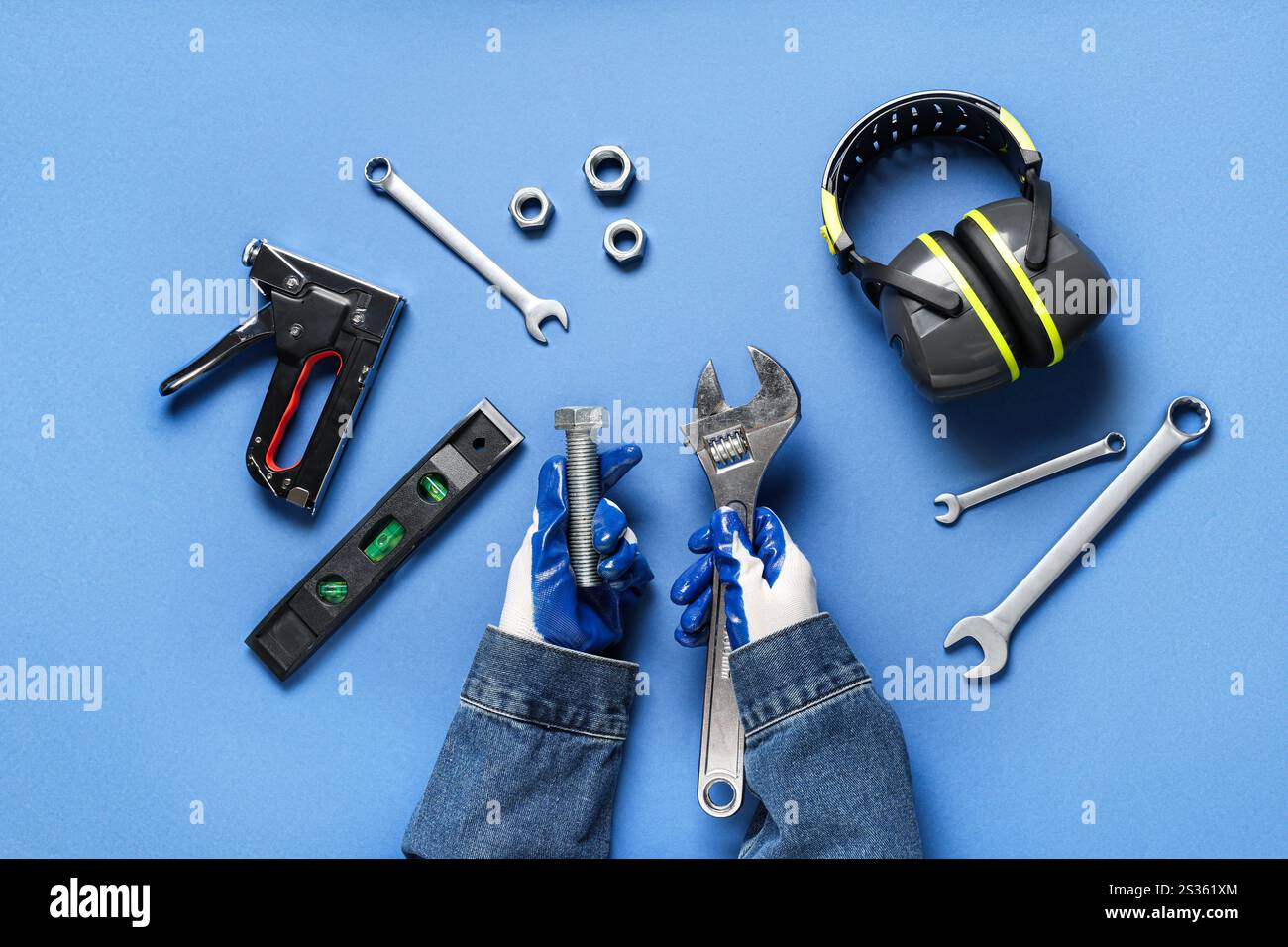 Mechanic's hands with bolt and tools on blue background Stock Photo - Alamy