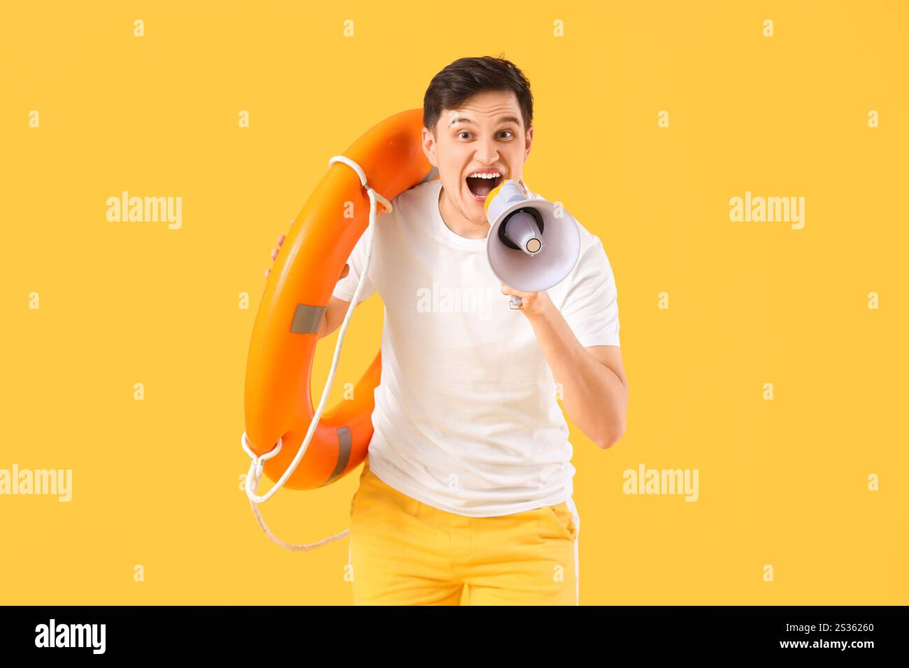 Male lifeguard with rescue ring and megaphone on yellow background ...