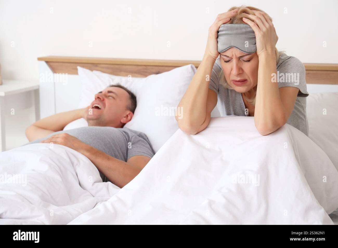 Irritated mature woman with her snoring husband in bedroom Stock Photo ...