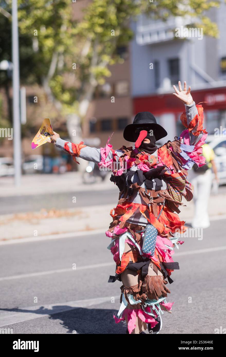 Street artist wearing a colorful costume is dancing during a parade ...