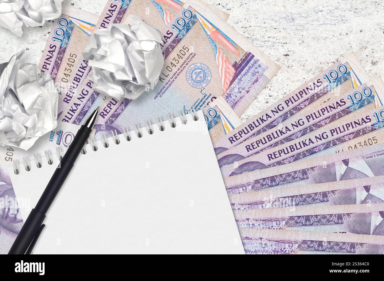 100 Philippine piso bills and balls of crumpled paper with notepad. Bad ...