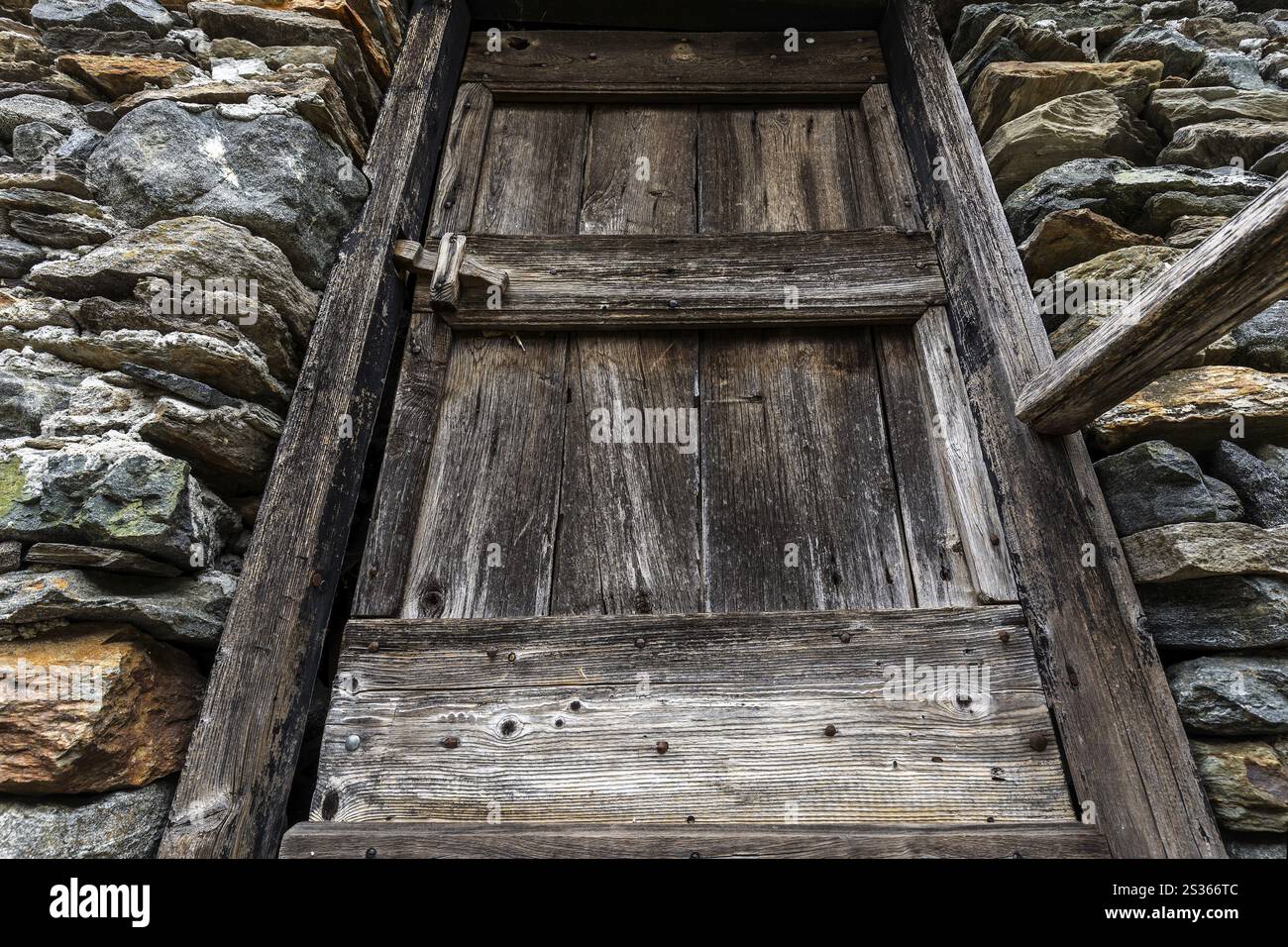 Old wooden door of a typical Ticino stone house in the mountain village ...