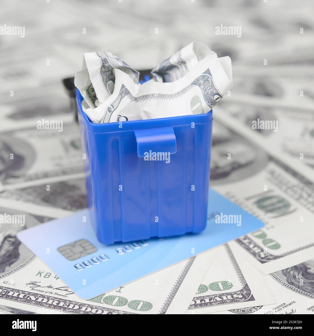 Dollar bills thrown into the trash and bank card. The concept of ...