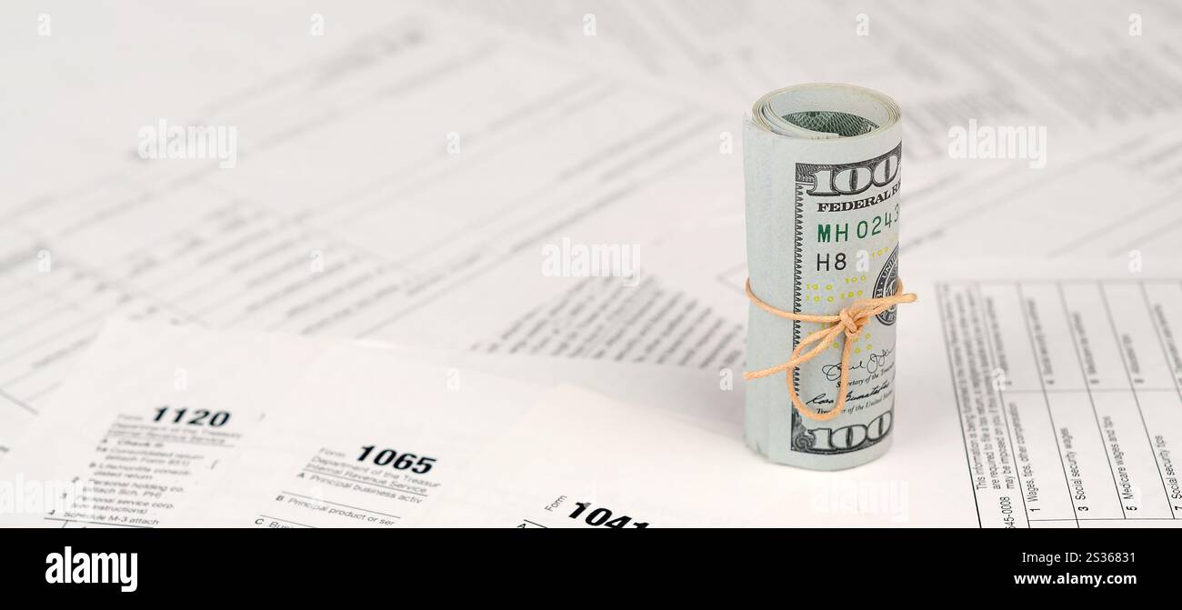 Tax forms lies near roll of hundred dollar bills. Income tax return ...