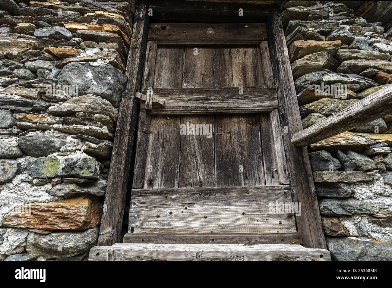 Old wooden door of a typical Ticino stone house in the mountain village ...