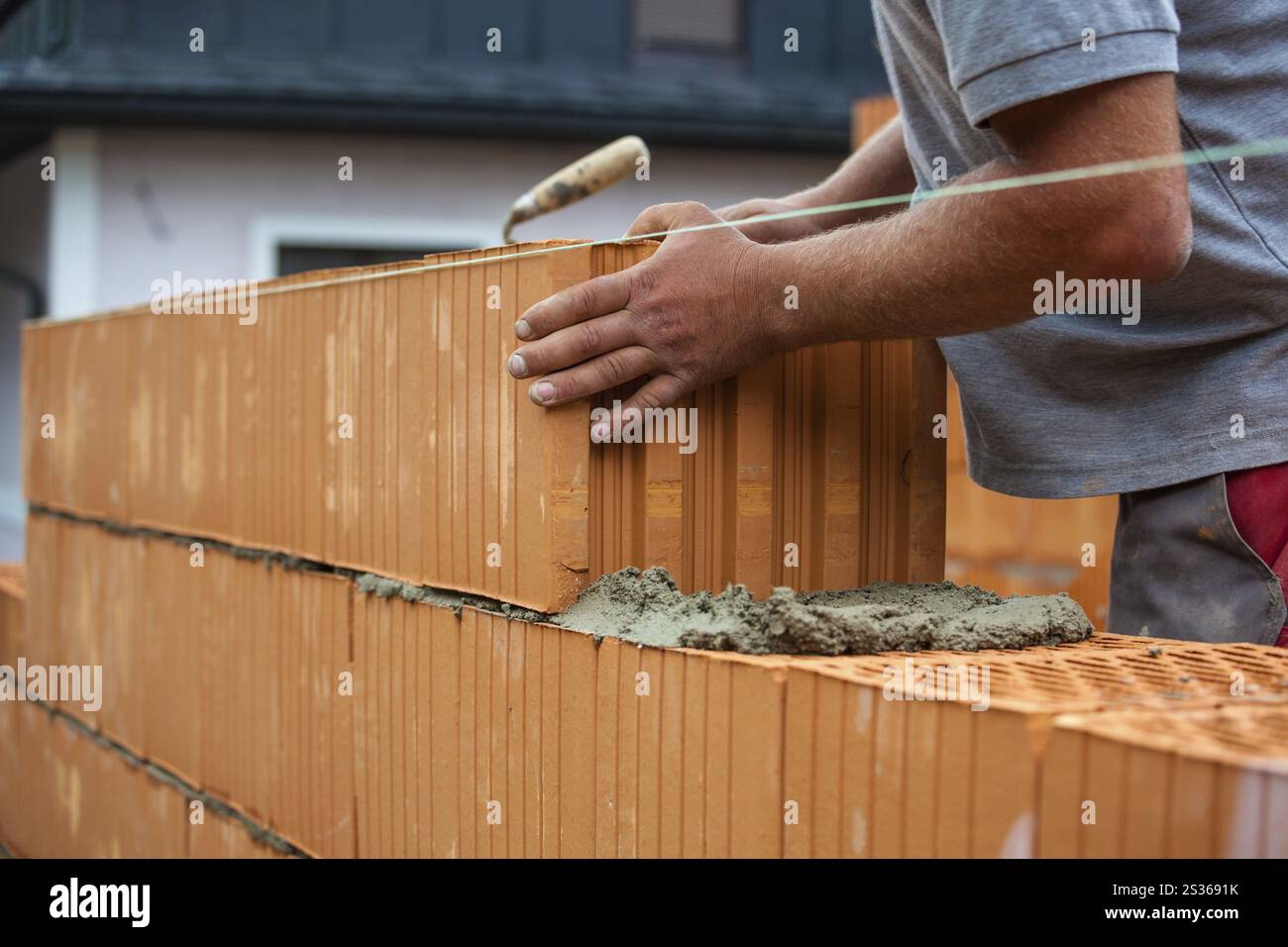 Anonymous construction worker on a building site erecting a brick wall ...
